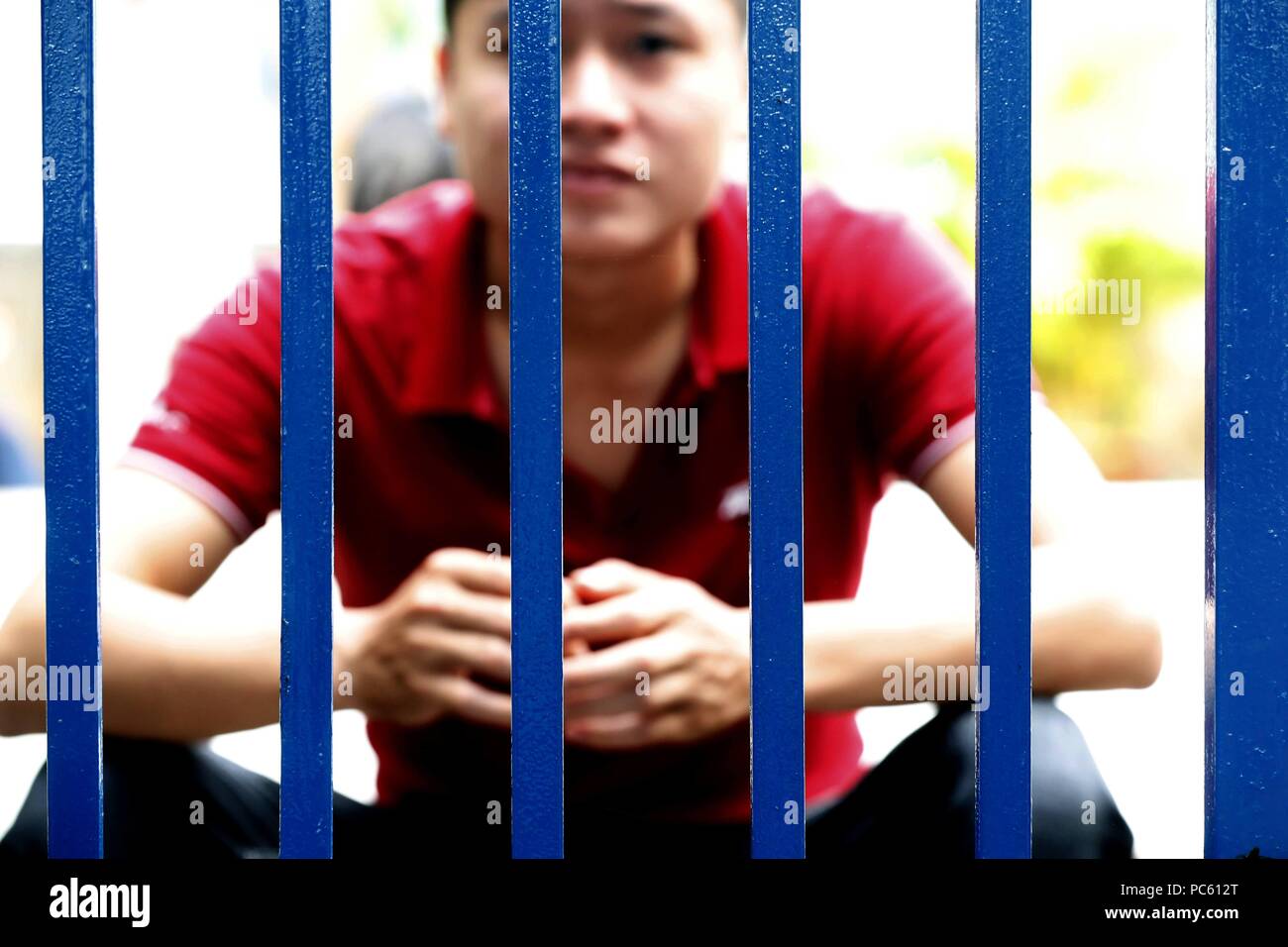 Young man behind close gate. Ho Chi Minh City. Vietnam. | usage ...