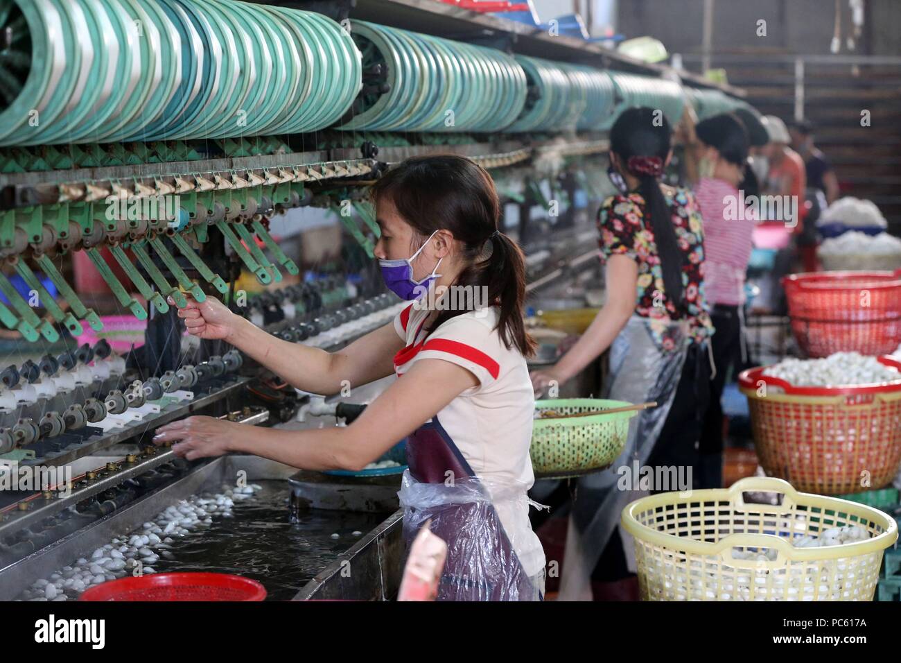 Traditional silk factory. Woman working on silk spinning machine. Dalat ...