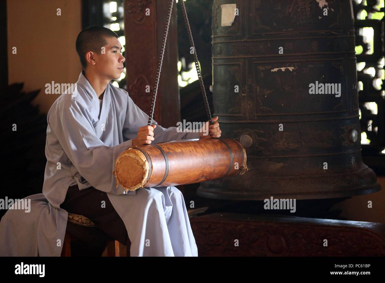 Linh An buddhist pagoda. Young monk ringing bell in monastery. Dalat ...