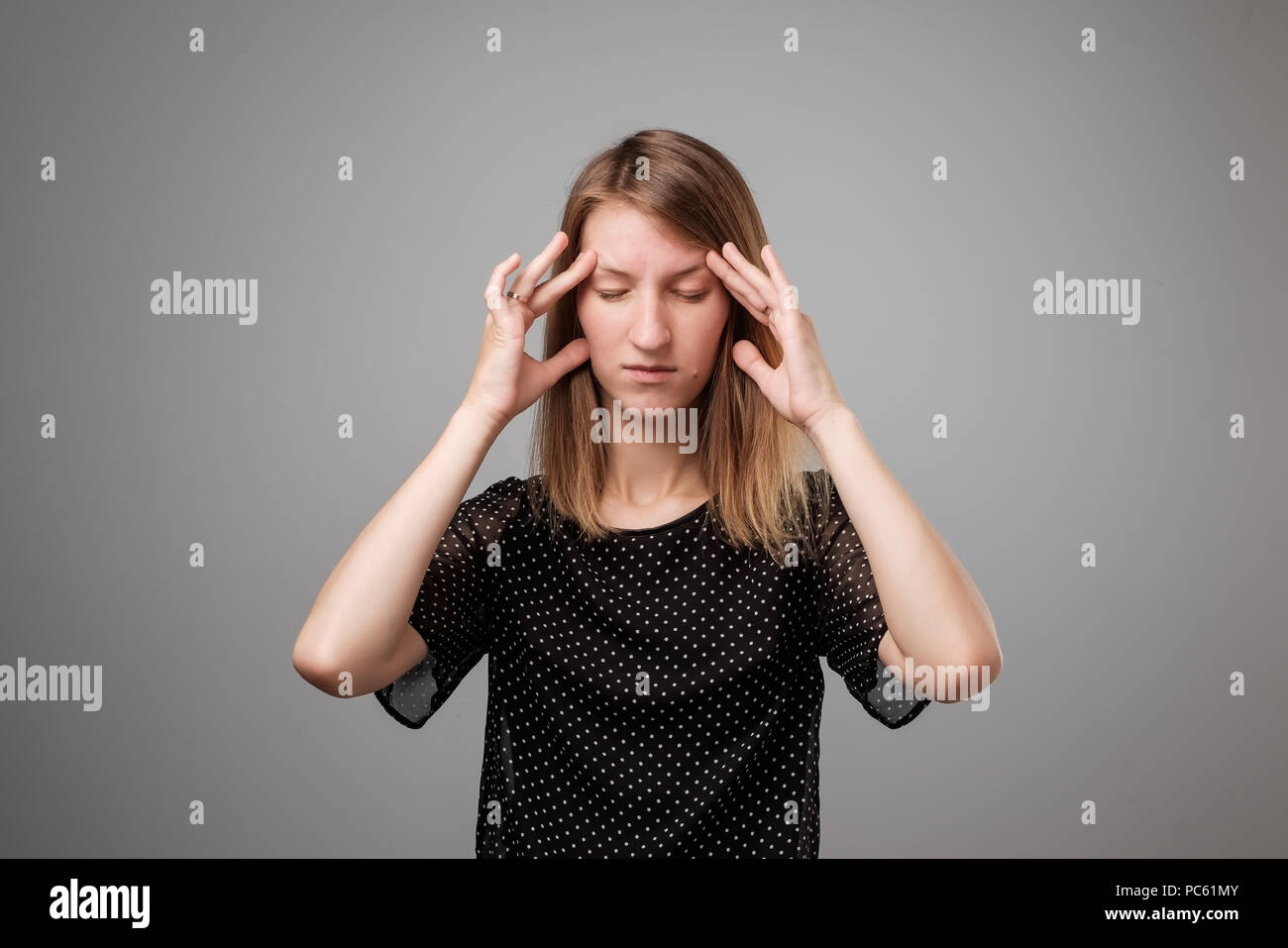 Portrait of beautiful young woman touching her temples feeling stress ...