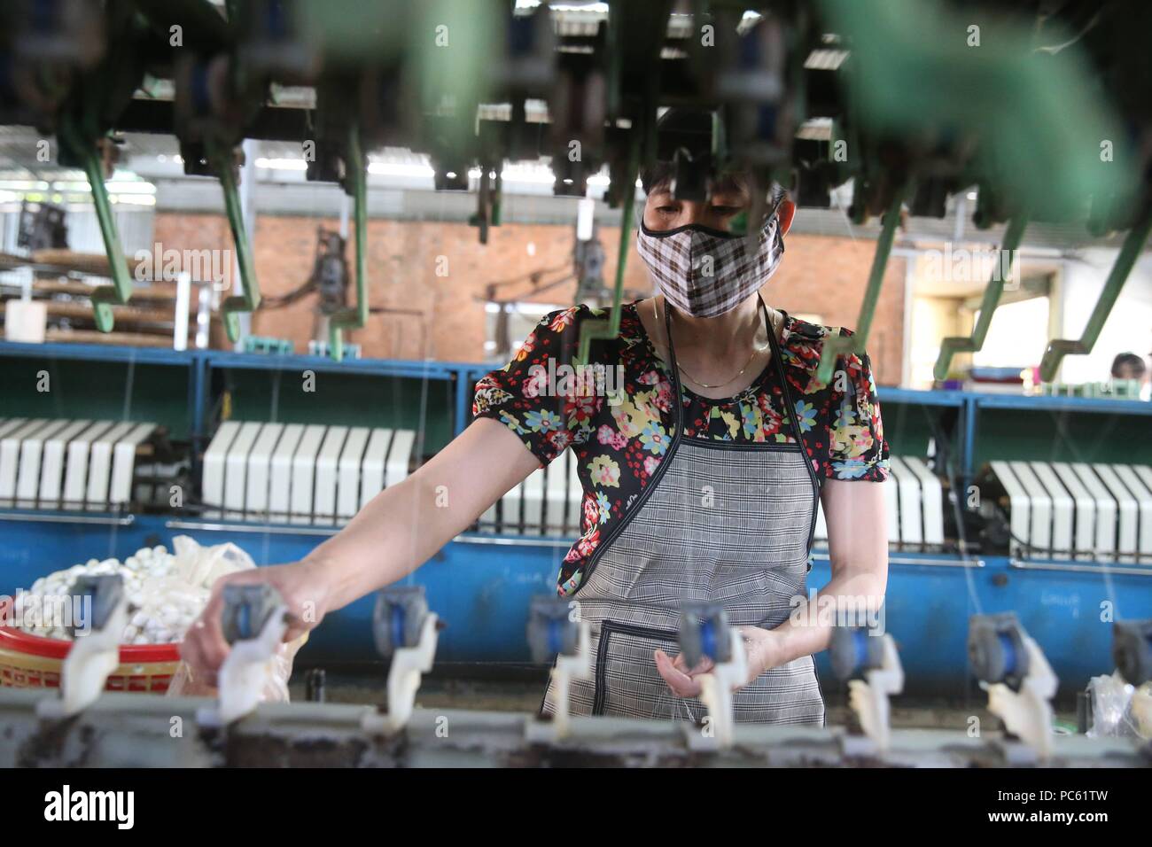 Traditional silk factory. Woman working on silk spinning machine. Dalat ...
