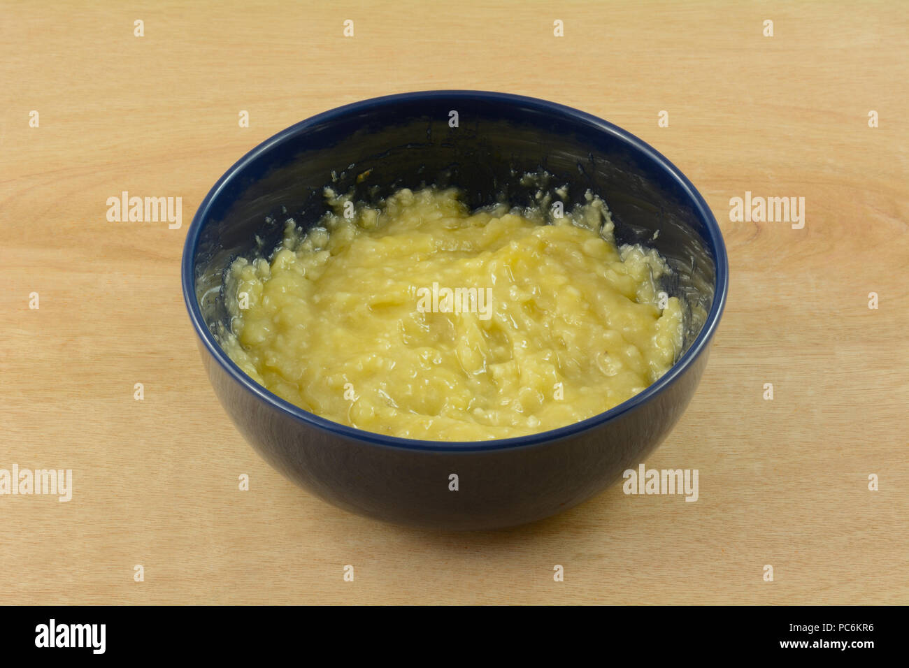 Banana roughly pureed in blue bowl as ingredient for banana bread Stock ...