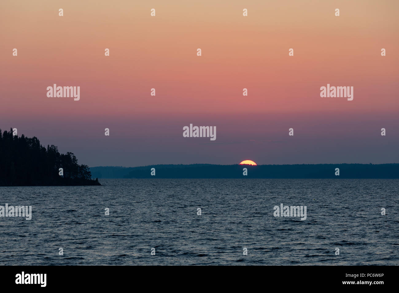 Big red sun rising over lake scene Stock Photo - Alamy