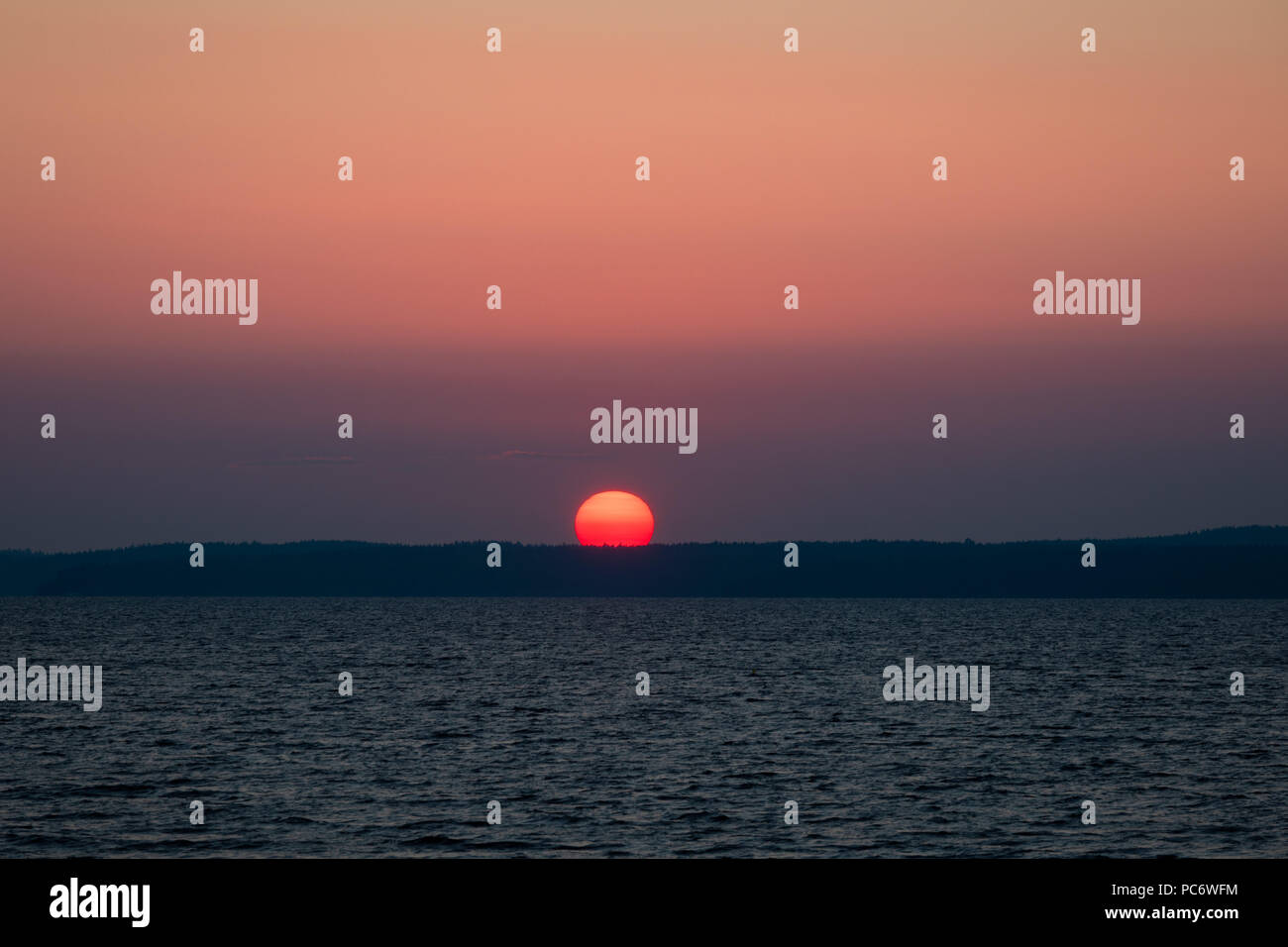 Big red sun rising over lake scene Stock Photo - Alamy