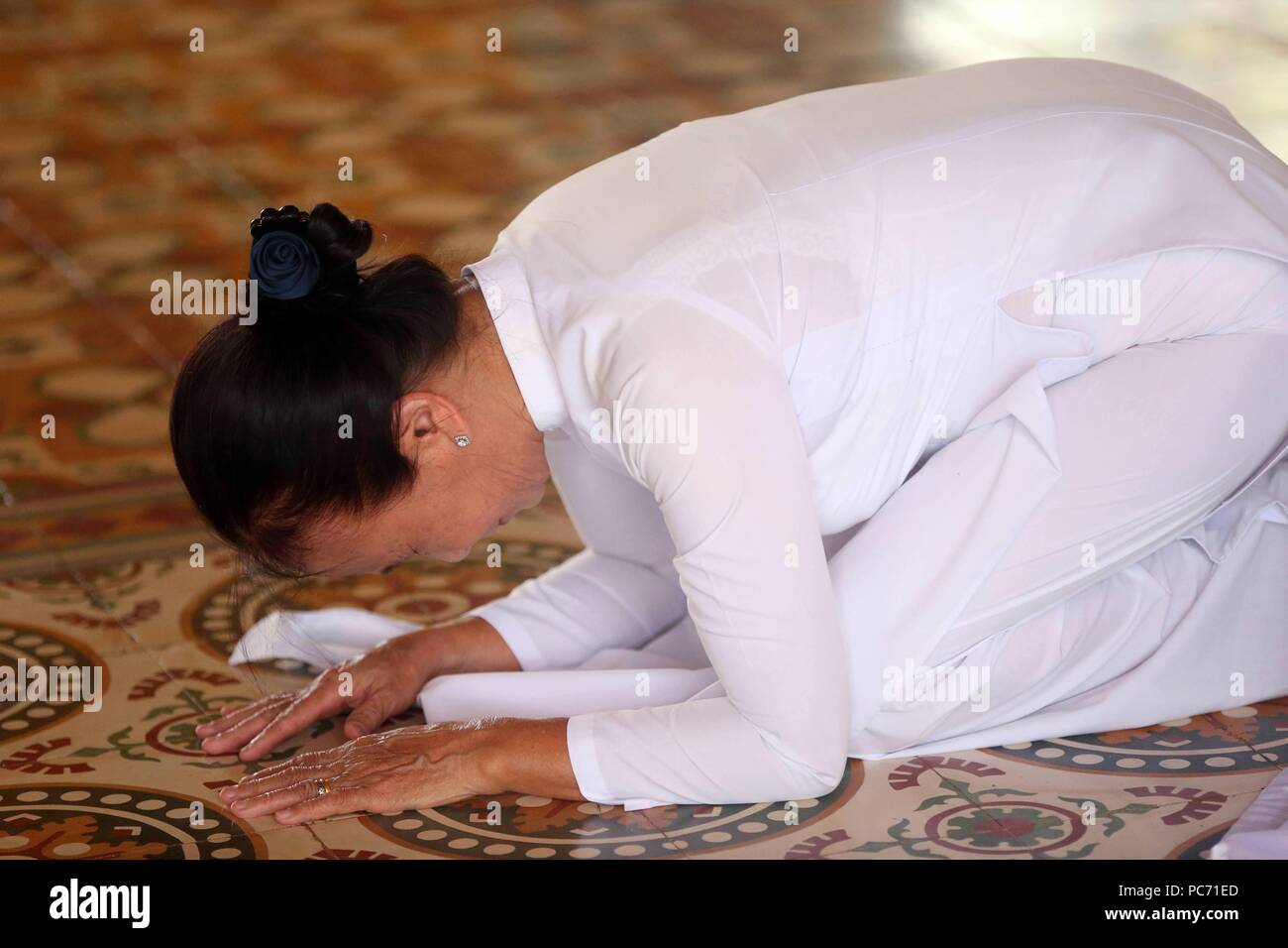 Cao Dai Holy See Temple. Caodaist service. Woman praying. Prostration ...
