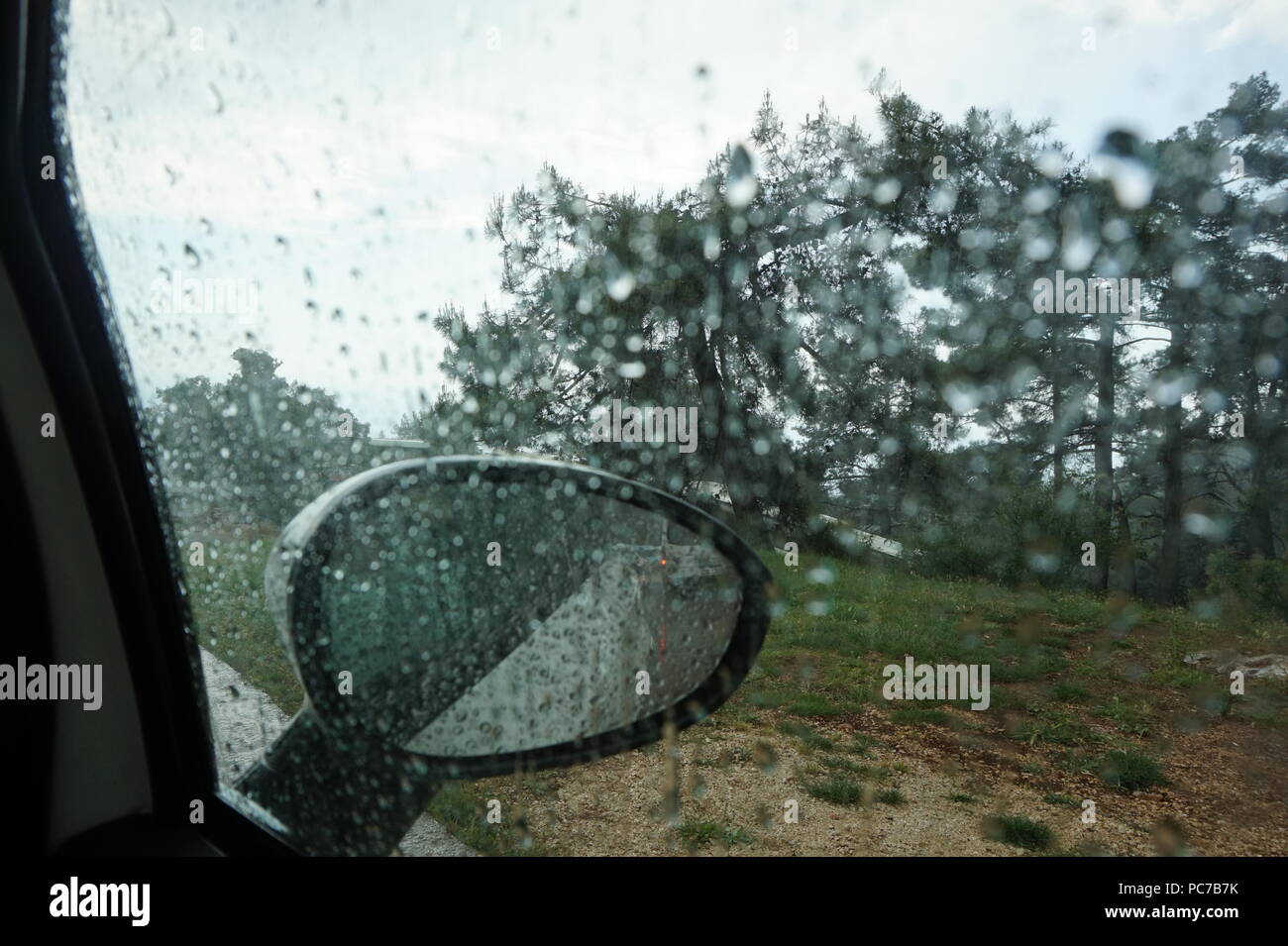 Large drops of rain flow down the windshield of the car, the view from ...