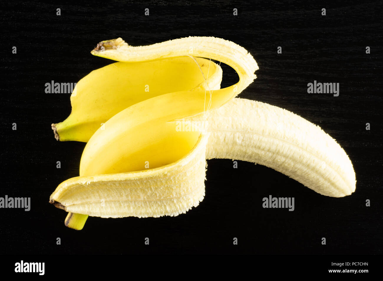 One whole opened fresh yellow banana flatlay on black wood Stock Photo ...