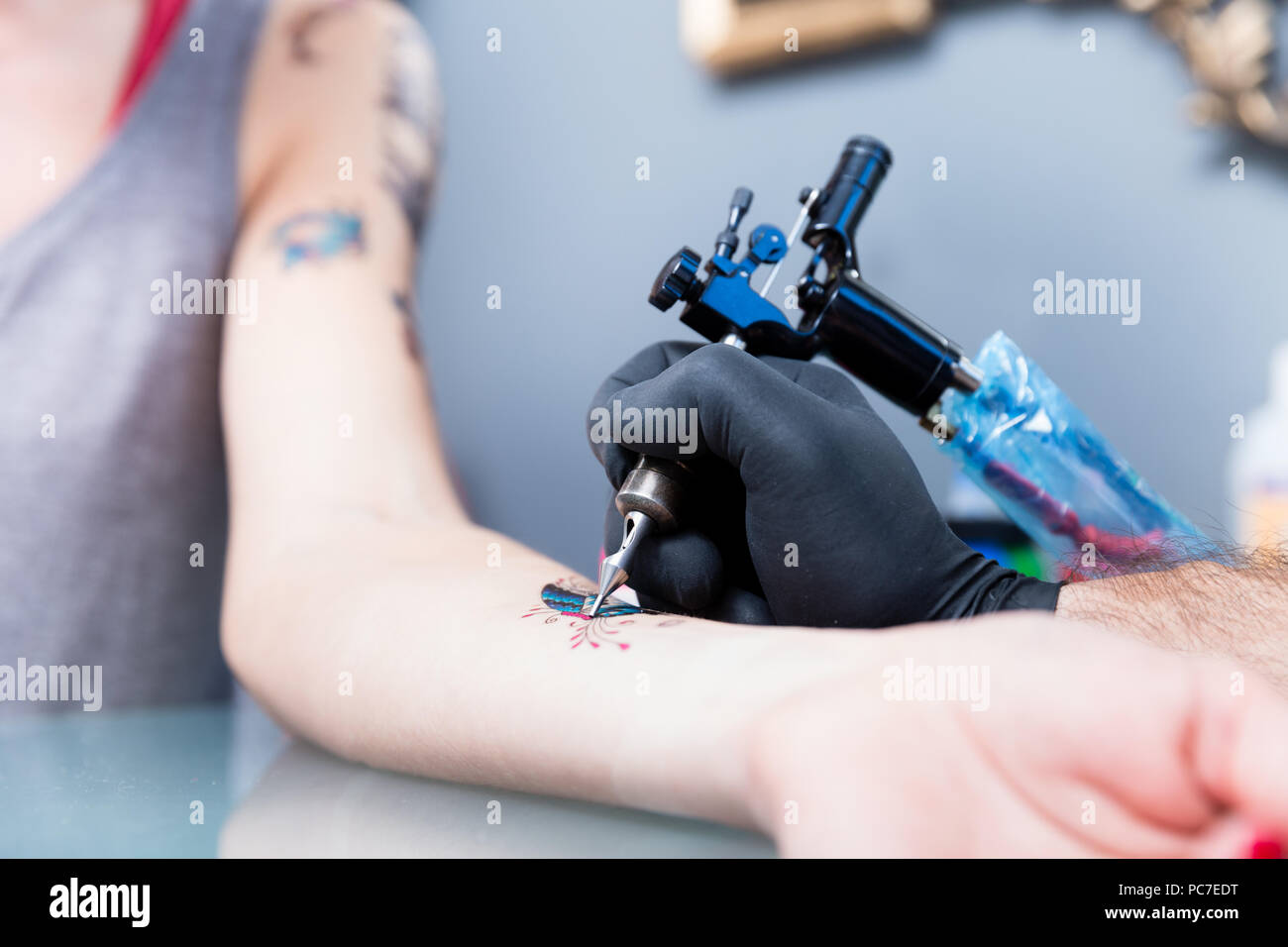Close-up of the hand of a tattoo artist shading a colorful butterfly ...