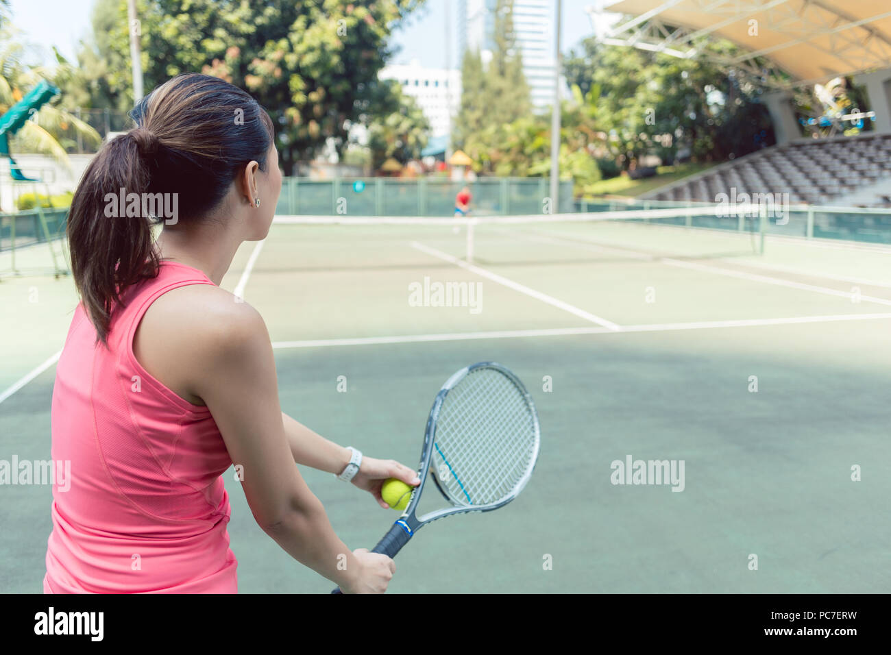 Rear view of a fit young woman playing tennis on a professional court ...