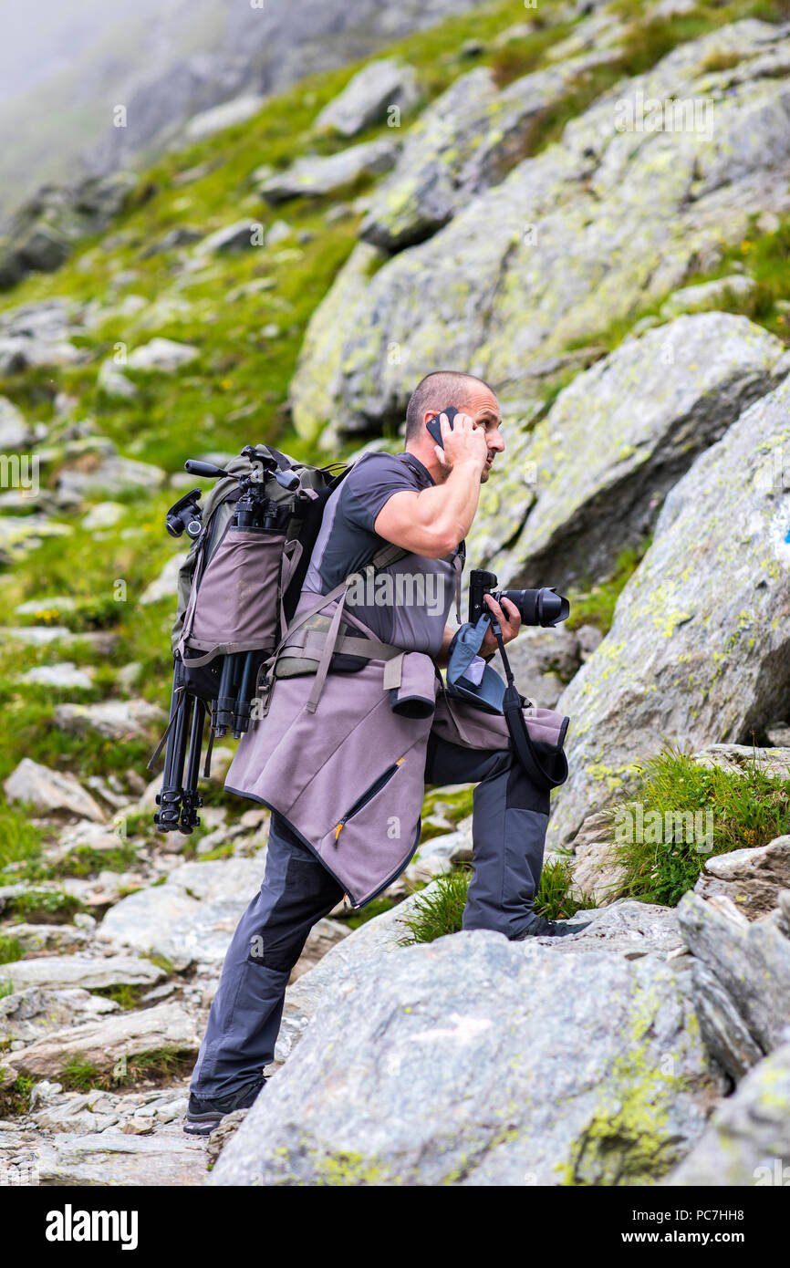 Photographer with backpack and camera hiking on a mountain trail Stock ...