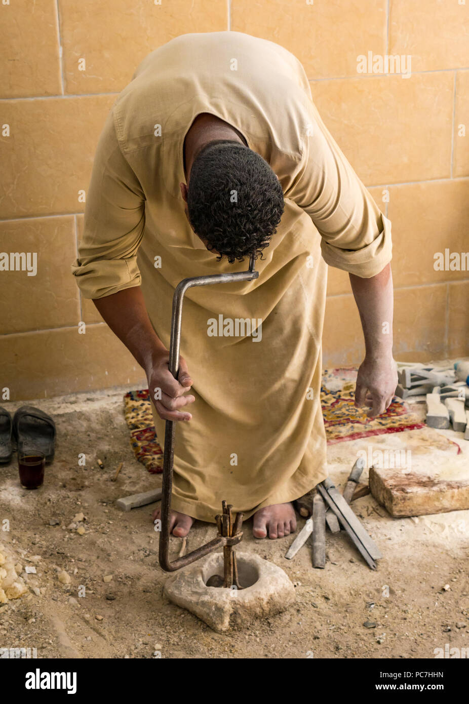 Egyptian workman using grinding tool to carve alabaster in workshop for ...
