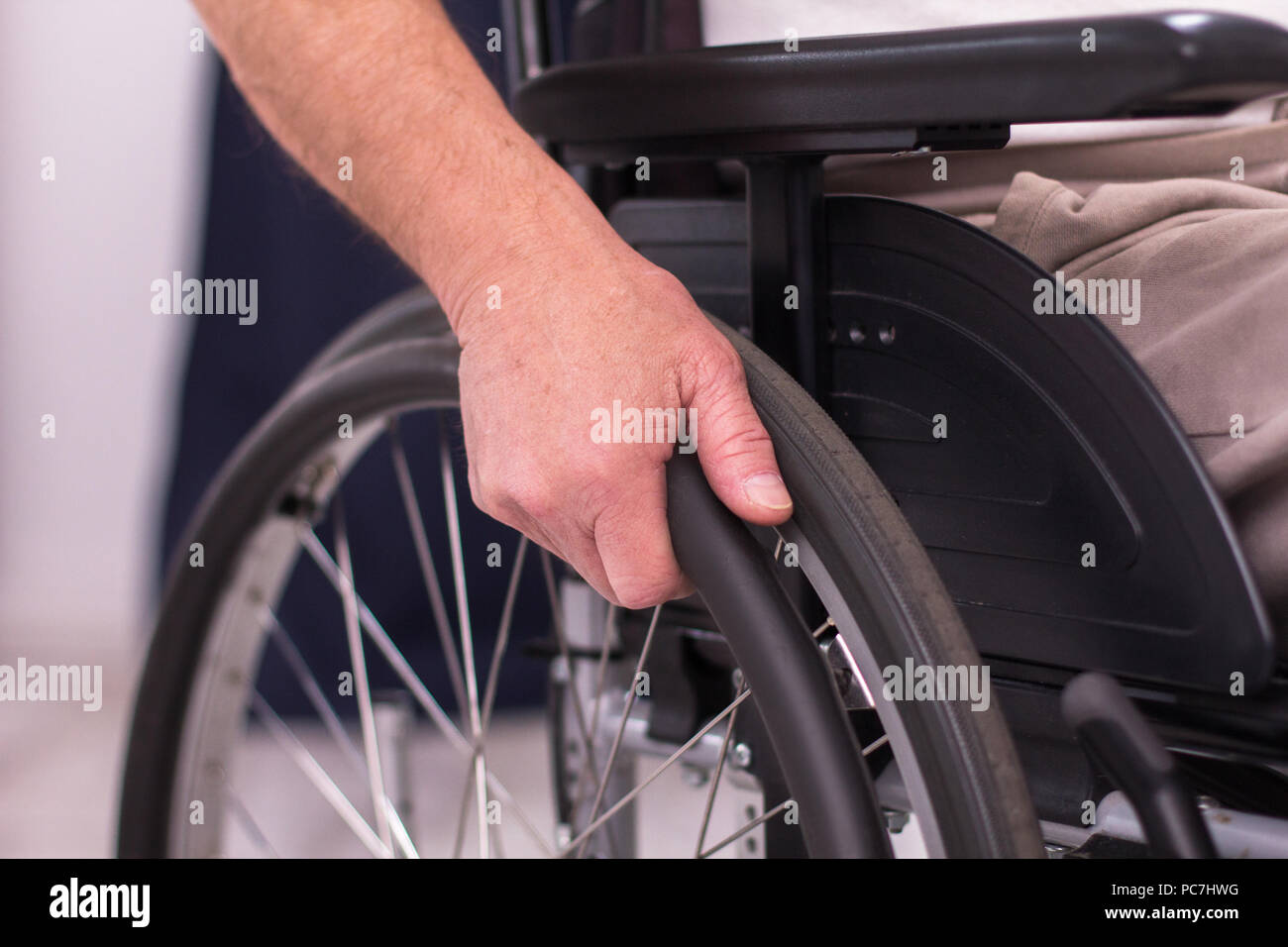 Close up of male hand rolling wheel of wheelchair. Hand of aged strong ...