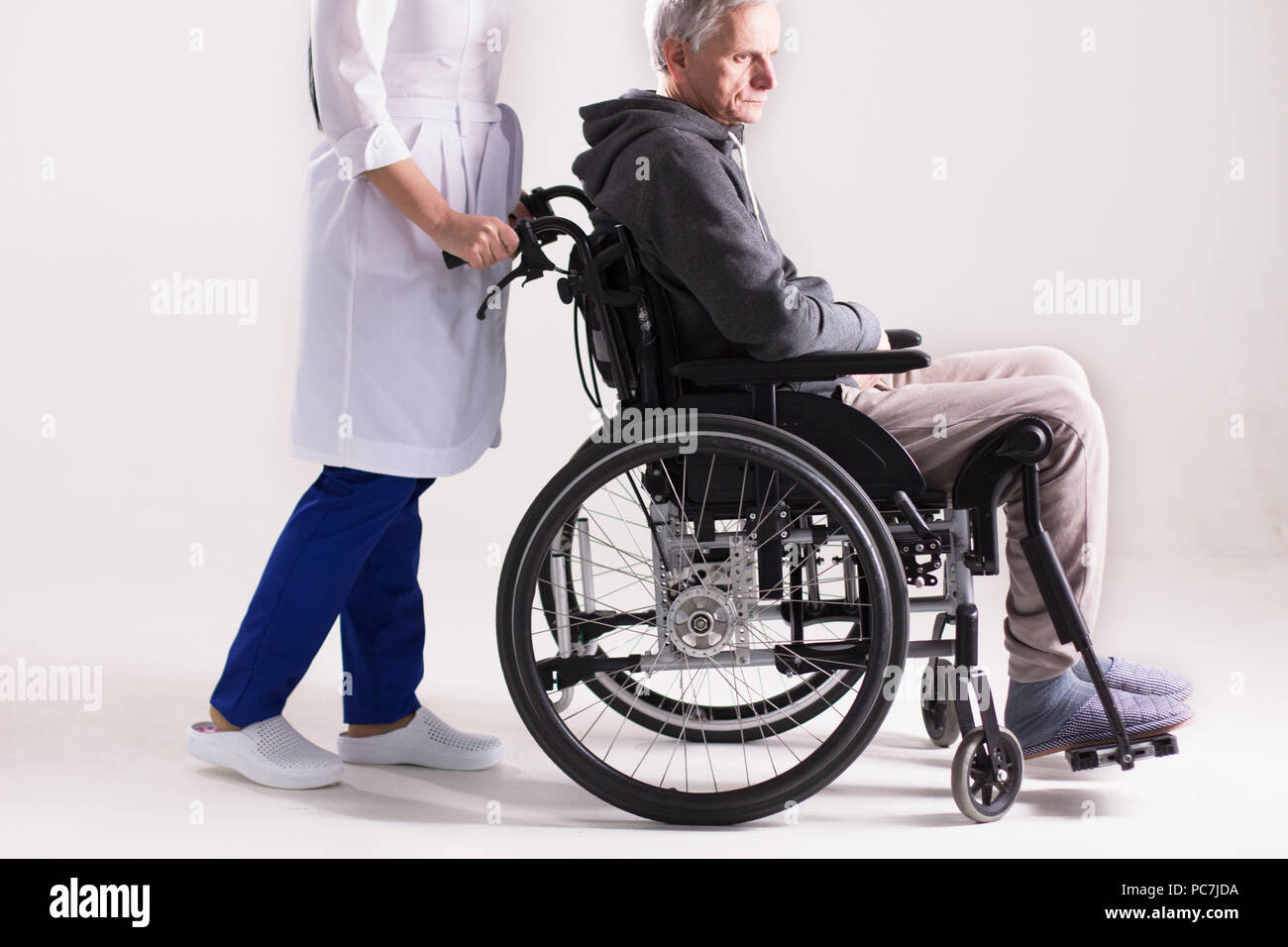 Studio shot of doctor pushing wheelchair with man it. Cropped picture ...