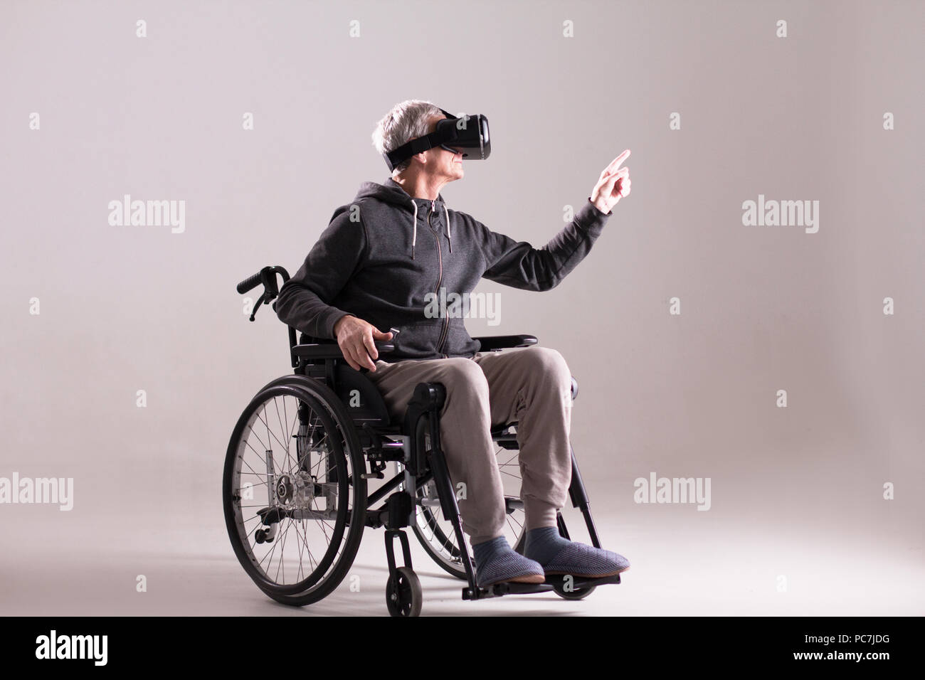 Studio shot of man in wheelchair wearing VR goggles. Disabled man in ...