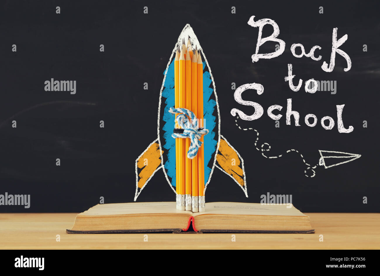 Back to school concept. rocket sketch and pencils over open book in ...