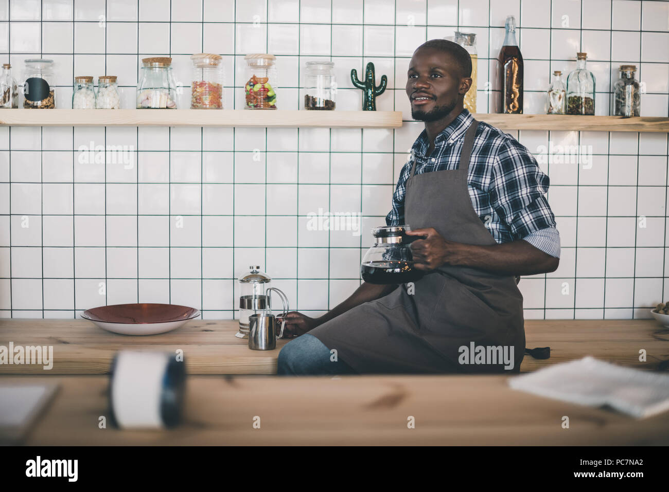 handsome african american barista holding coffee kettle on bar counter ...