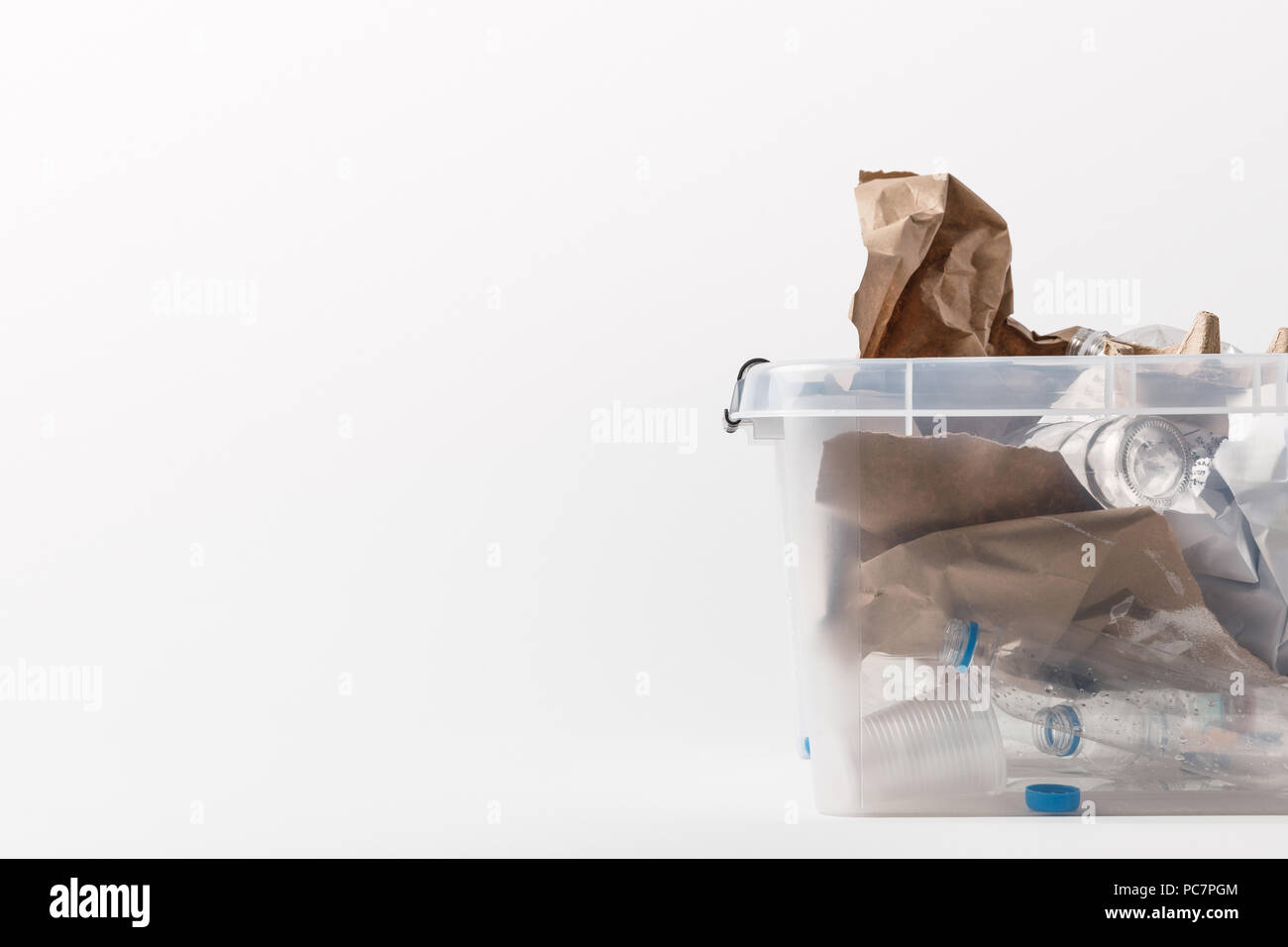 close up view of container with paper and plastic garbage isolated on ...