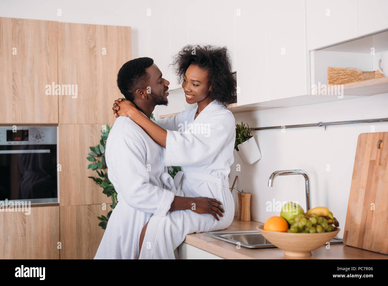Smiling african american couple hugging in kitchen Stock Photo - Alamy