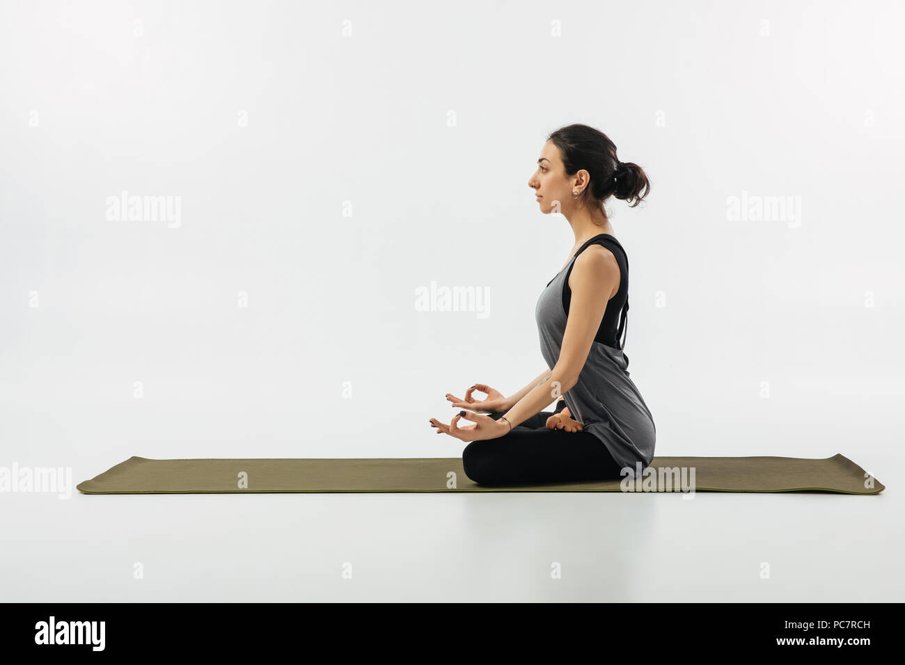 side view of woman meditating in yoga lotus pose isolated on white ...