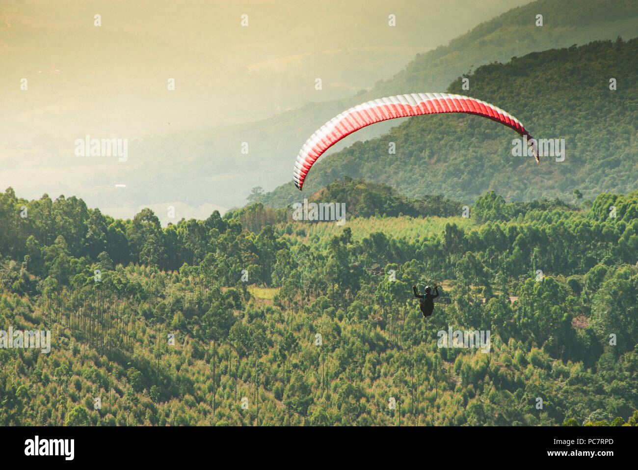Paraglider flying on the beautiful sunny sky over the green mountains ...