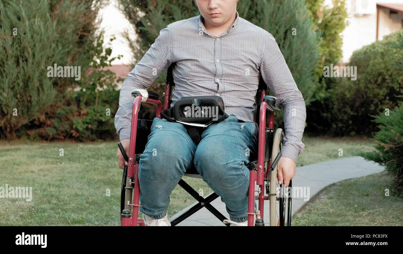 A disabled man in a wheelchair chair uses a virtual reality helmet ...