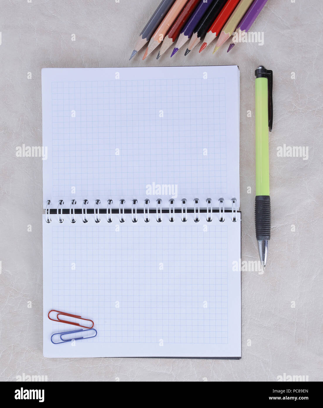 open Notepad and colored pencils on paper background.photo with copy ...