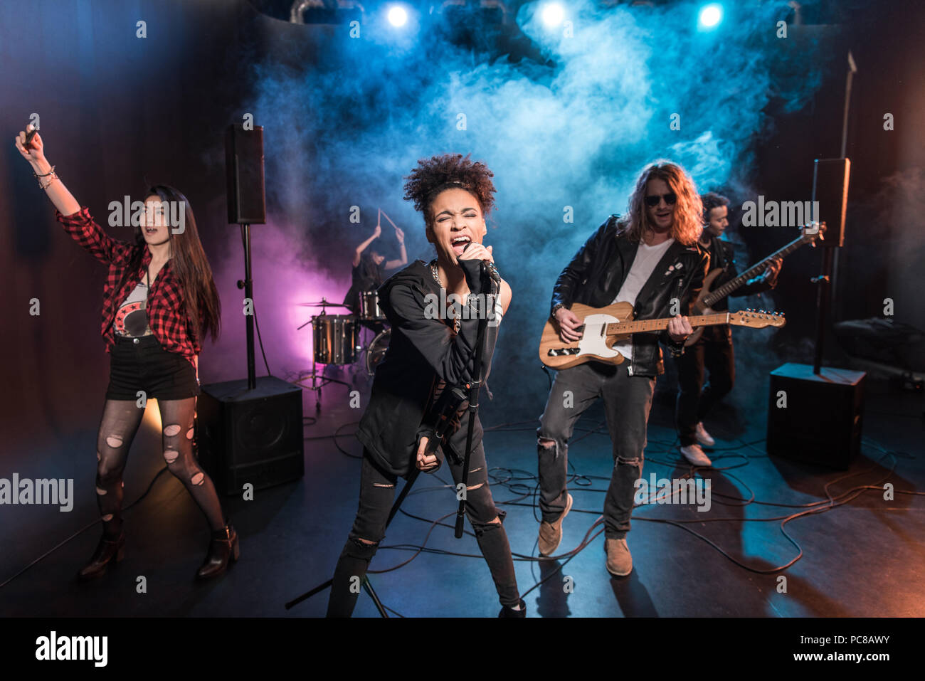 Female singer with microphone and rock and roll band performing hard ...