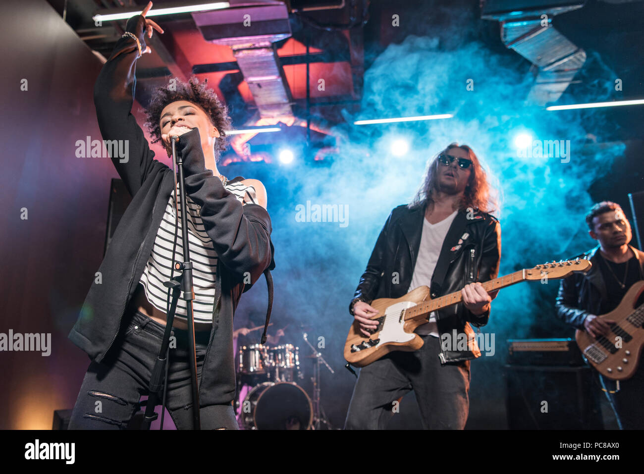 Female singer with microphone and rock and roll band performing hard ...