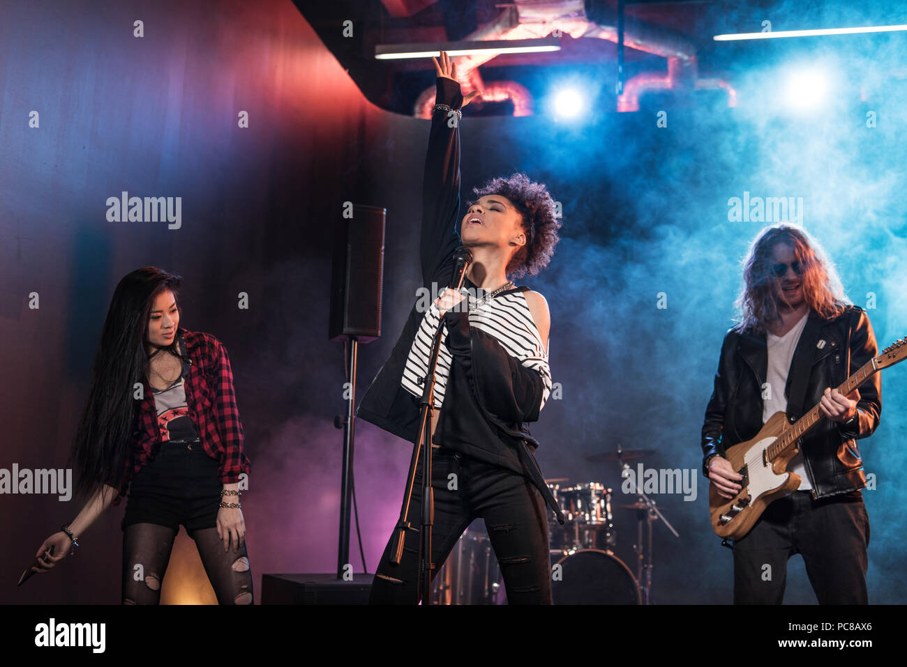 Young multiethnic rock and roll band performing hard rock music on ...