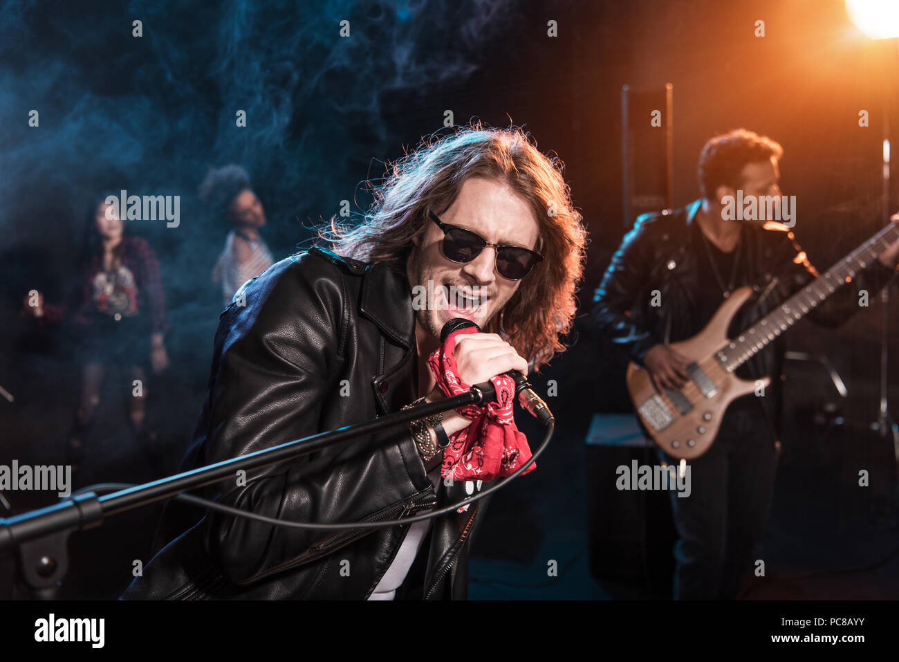 Male singer with microphone and rock and roll band performing hard rock ...