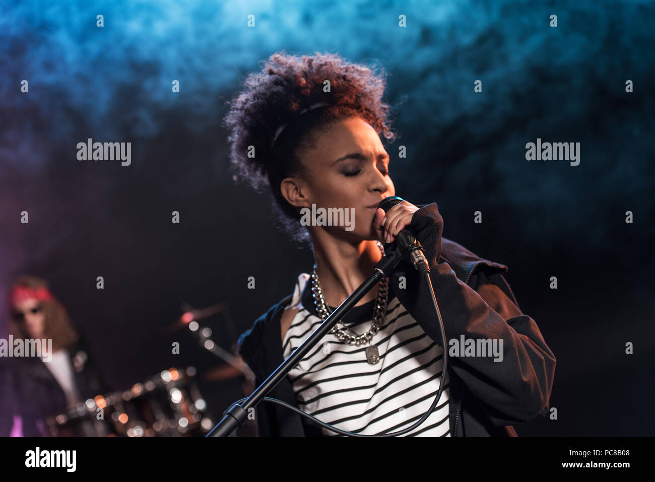 Female singer with microphone and rock and roll band performing hard ...