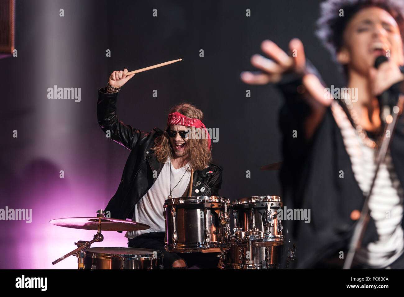 Smiling young man playing drums set with singer on stage Stock Photo ...