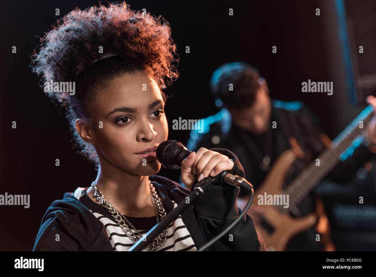Female singer with microphone and rock and roll band performing hard ...