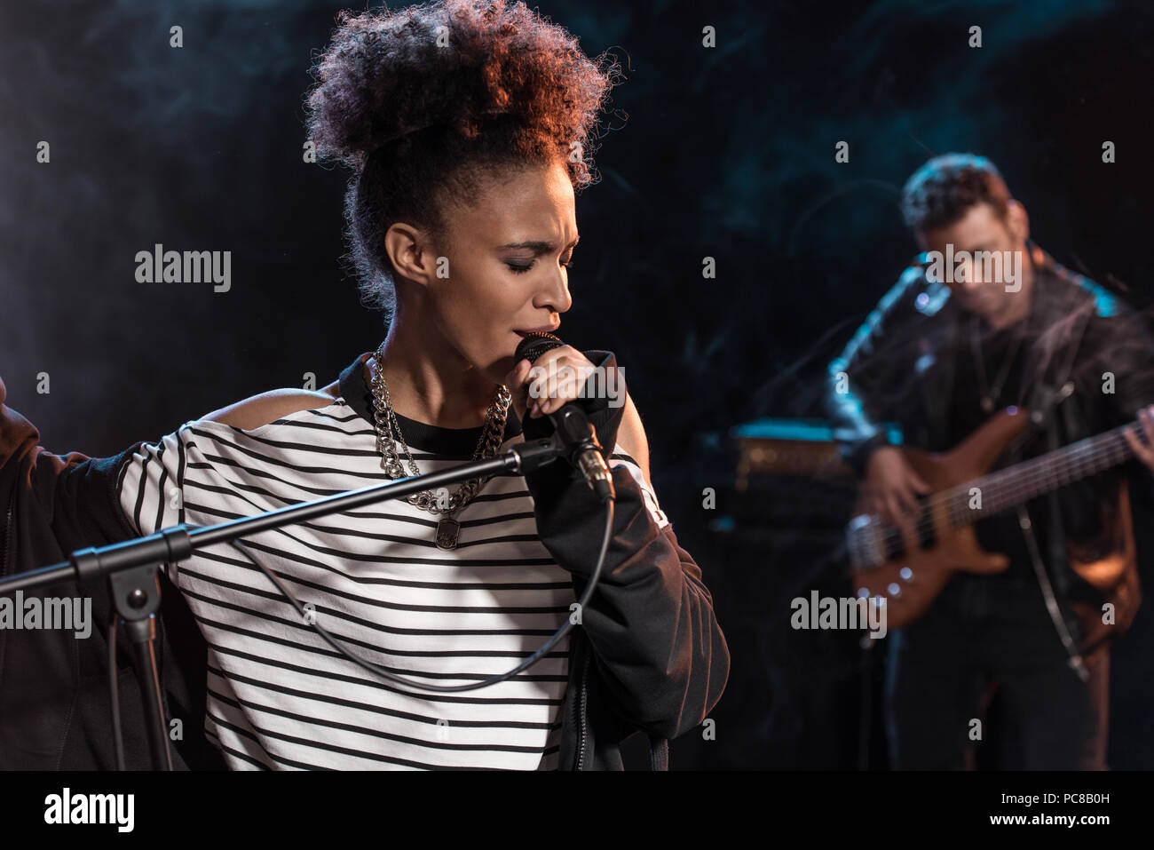 Female singer with microphone and rock and roll band performing hard ...
