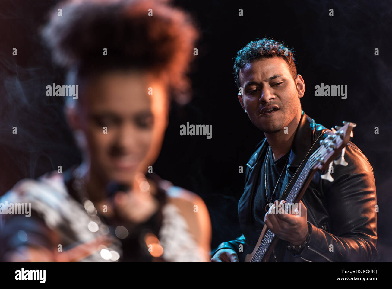 Young electric guitar player performing hard rock music with singer on ...