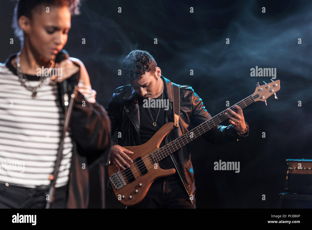 Young electric guitar player performing hard rock music with singer on ...