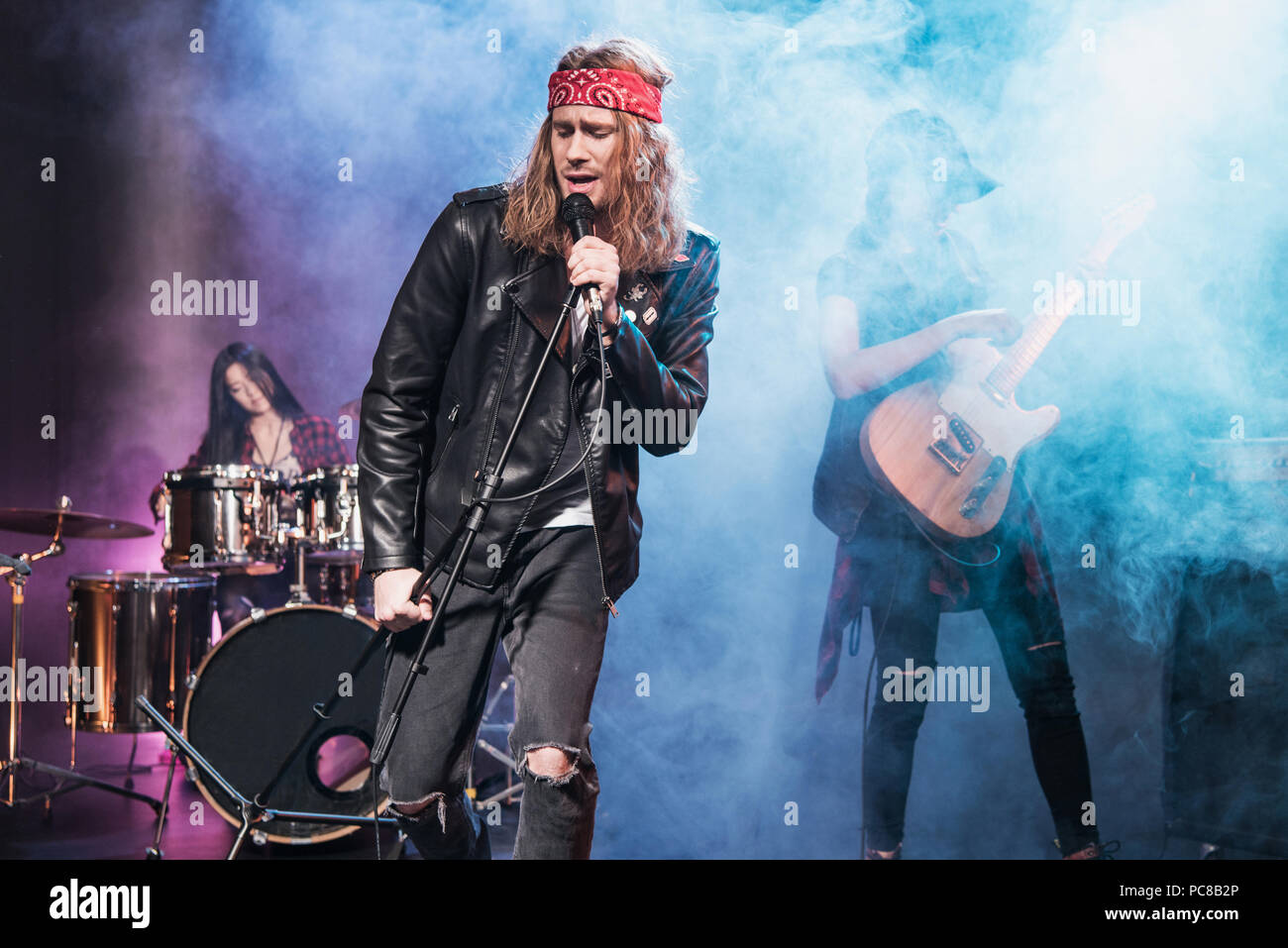Handsome singer with rock and roll band performing music on stage Stock ...