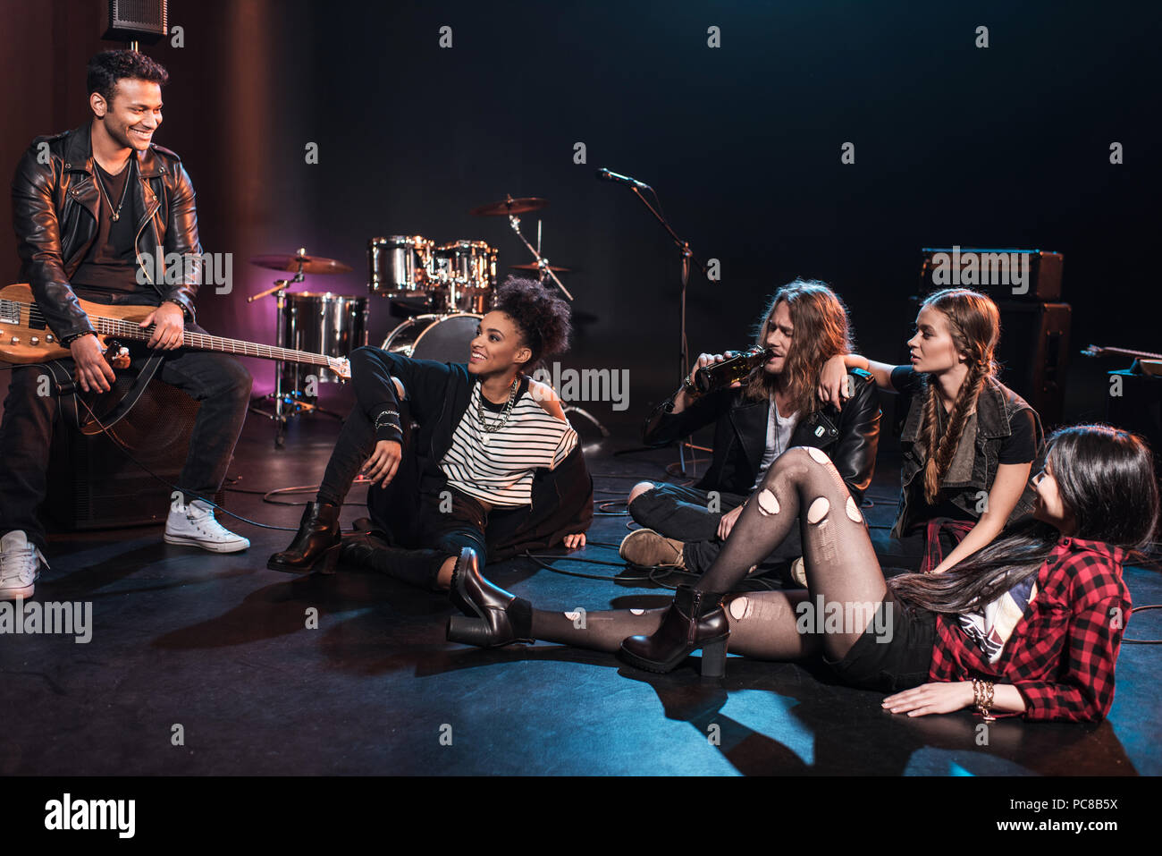 Young rock and roll band sitting together and drinking beer after ...