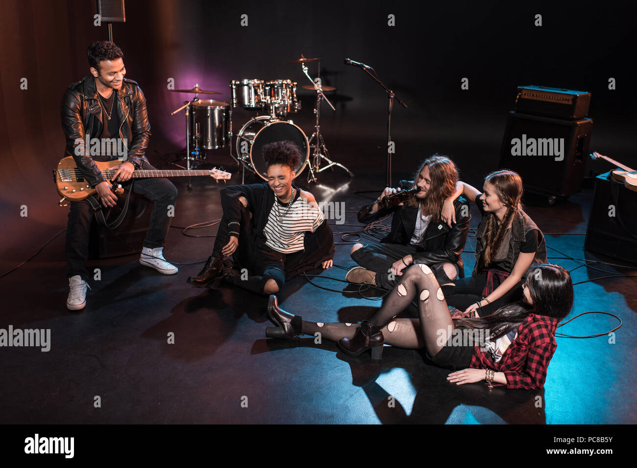 Young rock and roll band sitting together and drinking beer after ...