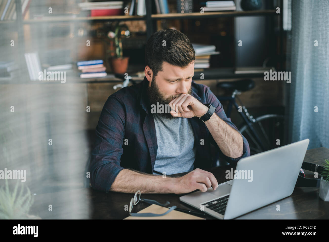portrait of tired businessman typing on laptop at workplace at home ...