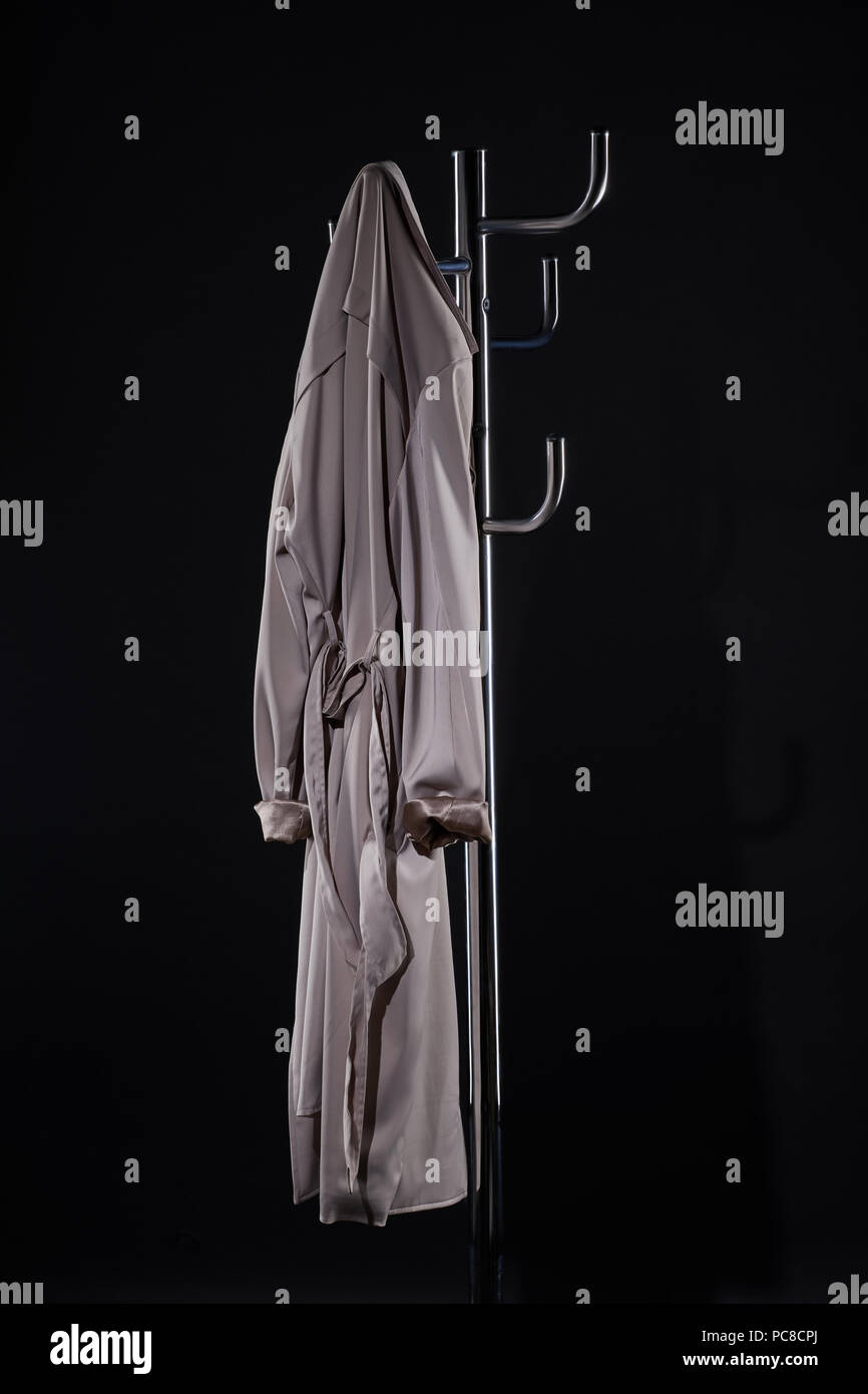 trench coat hanging on coat rack isolated on black Stock Photo - Alamy