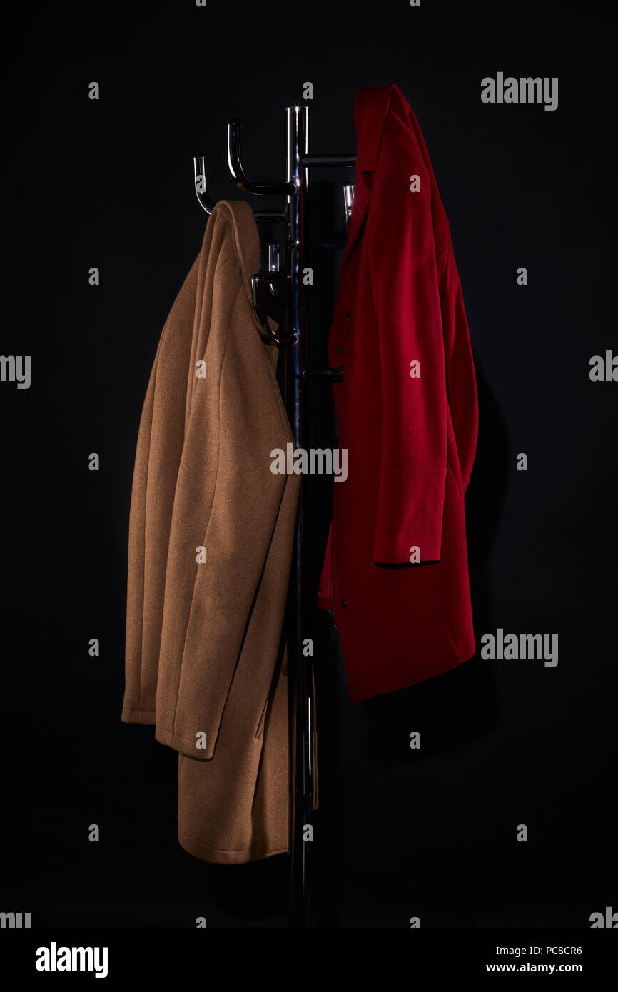 classic coats on coat rack isolated on black Stock Photo - Alamy