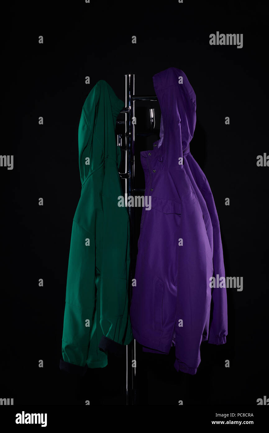 raincoats hanging on coat rack isolated on black Stock Photo - Alamy