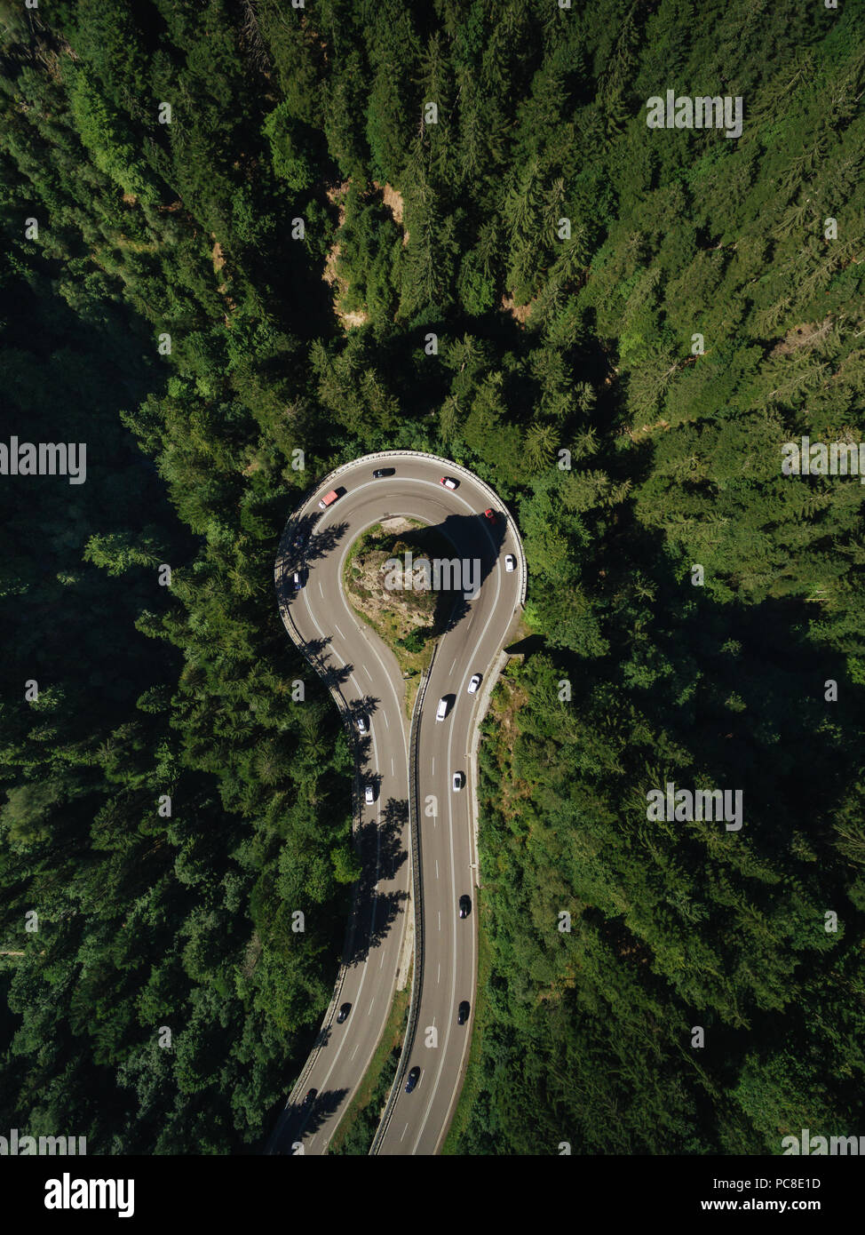 aerial view of cars passing road around rock in forest Stock Photo - Alamy