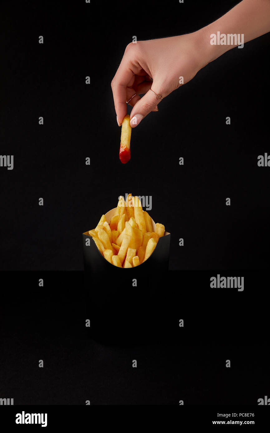 cropped shot of woman folding french fry poured into ketchup over box ...