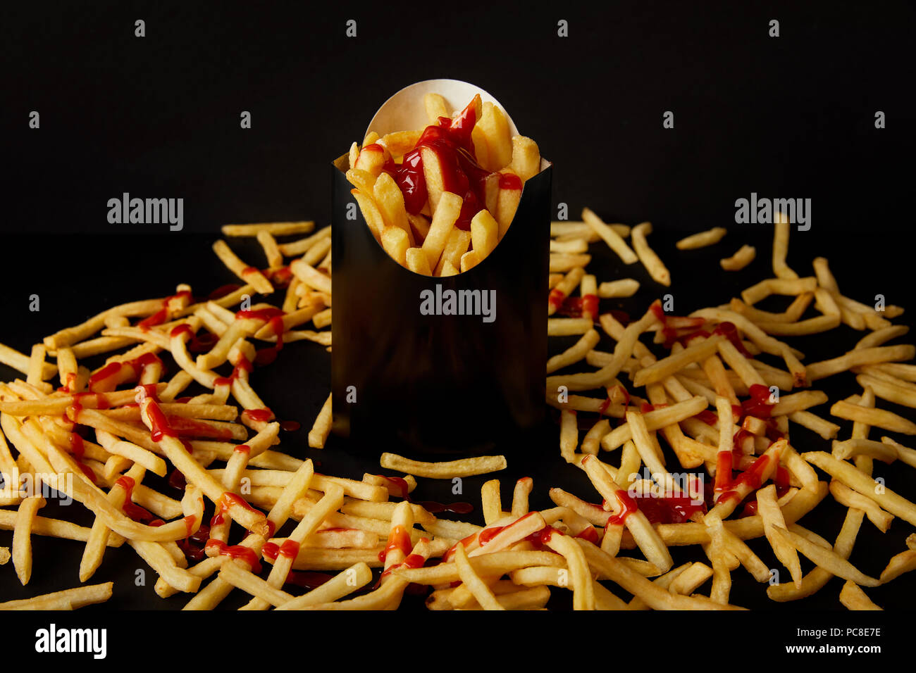 french fries in black box surrounded with messy fries on tabletop ...