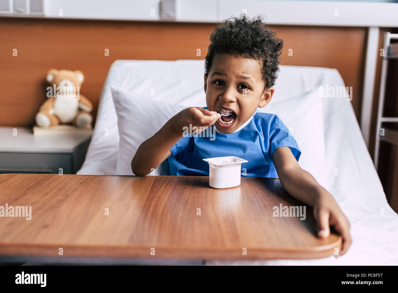 portrait of little african american boy eating yogurt while resting in ...