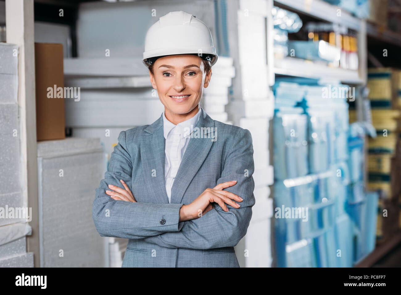 female inspector in helmet posing with crossed arms in shipping stock ...