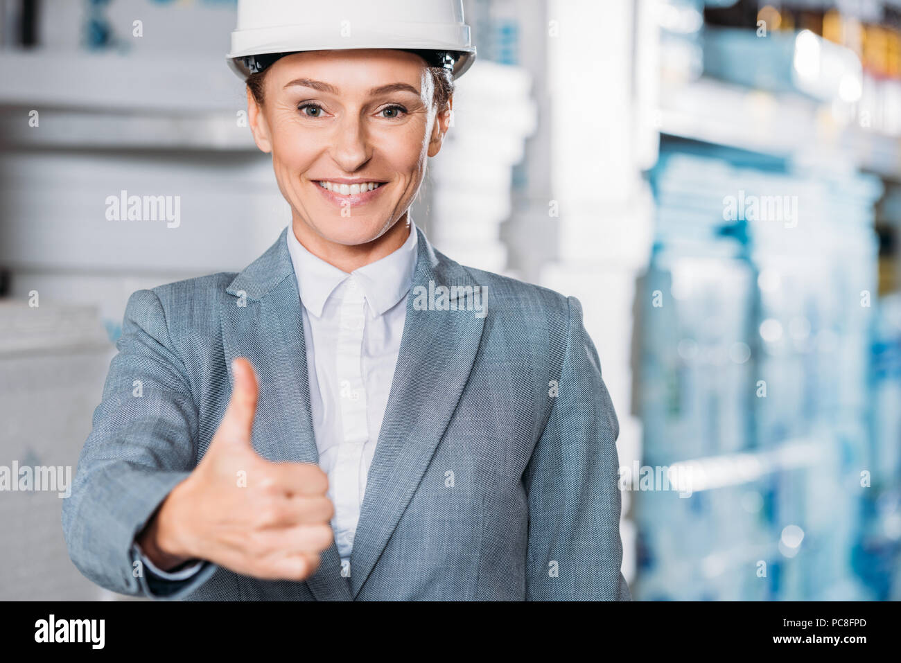 female inspector in helmet showing thumb up in warehouse Stock Photo ...