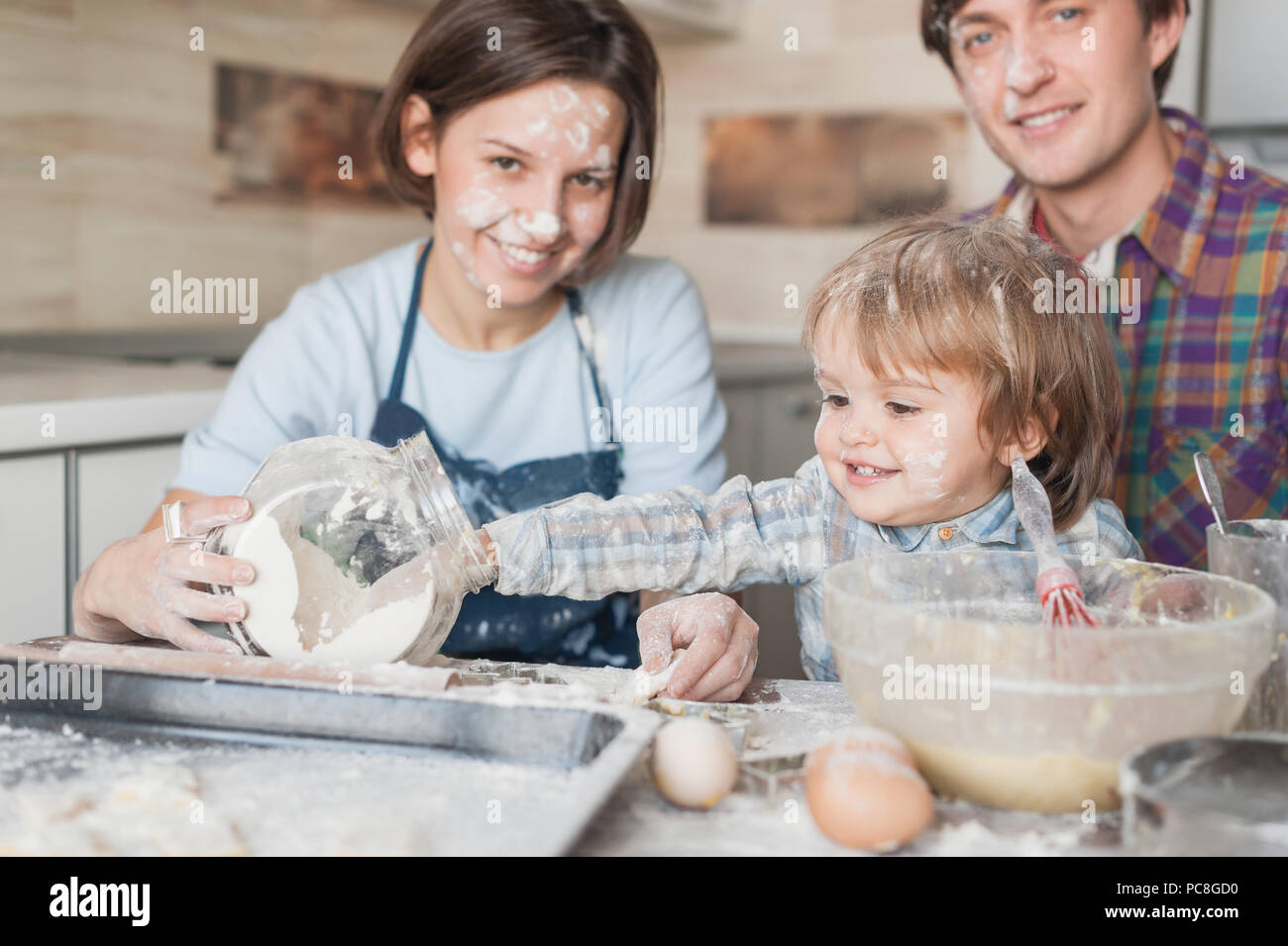 adorable little kid helping his parents with cooking at kitchen Stock ...